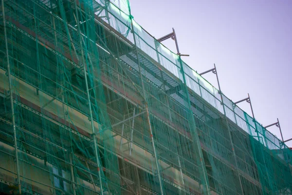Multistory building facade covered with green protective construction ...
