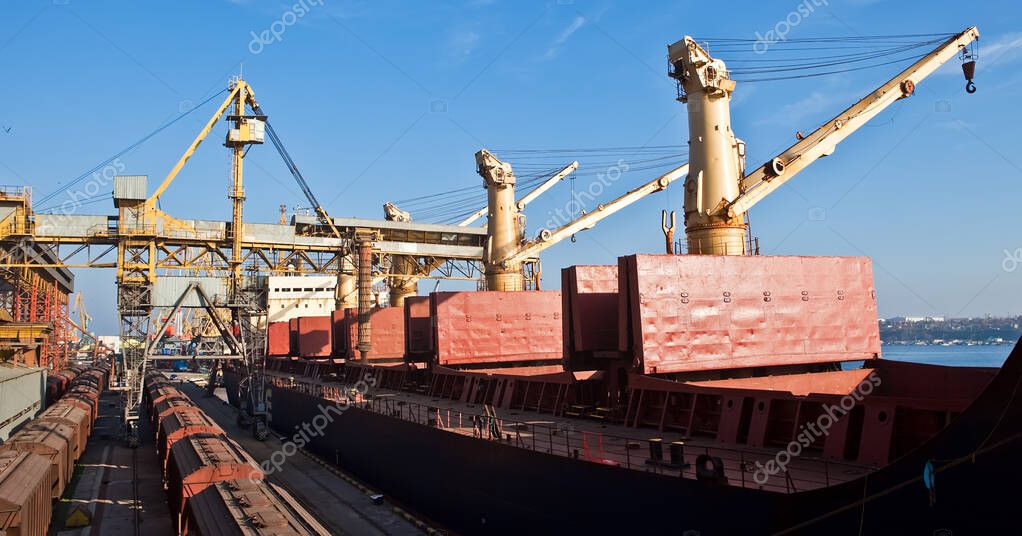 Loading grain into holds of sea cargo vessel in seaport from silos of ...