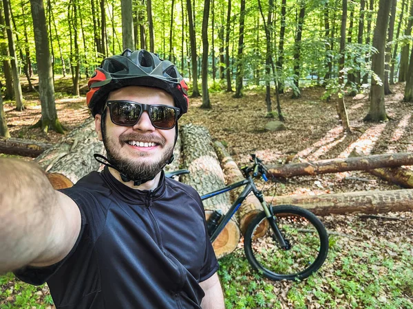 Happy cyclist in the rural area with his mountain bike behind. A ...