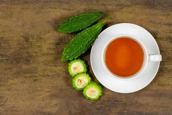 Bitter gourd or bitter melon tea in white cup and fresh bitter gourd on ...