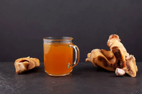Beef Bone Broth in clear mug on dark background. Selective focus, copy ...