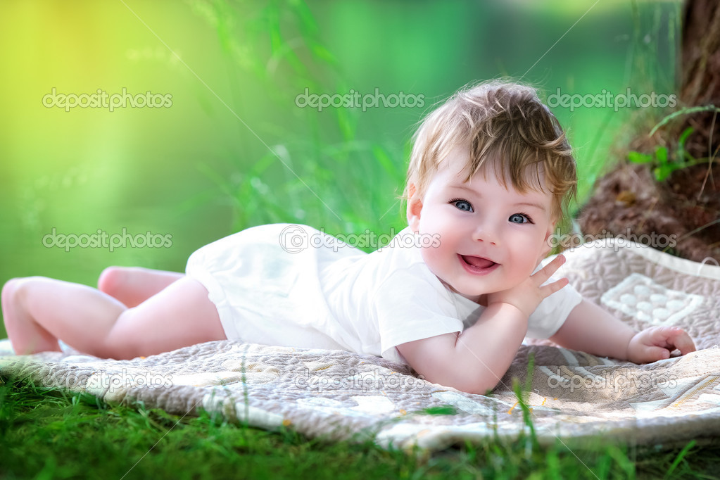 Happy little baby having fun in the park on the lake shore backg ...