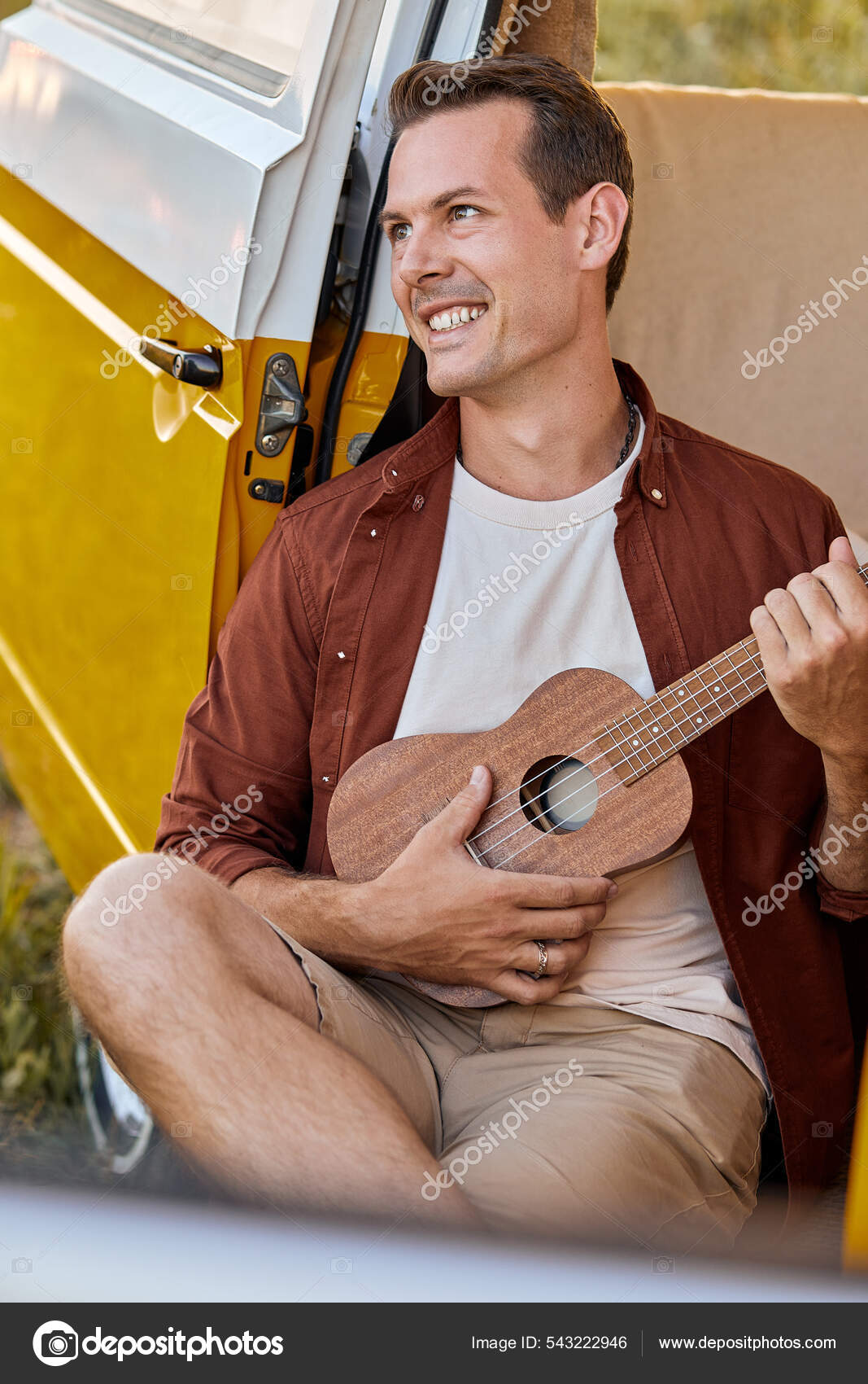 Handsome caucasian man, sitting inside DIY camper can with ukulele ...
