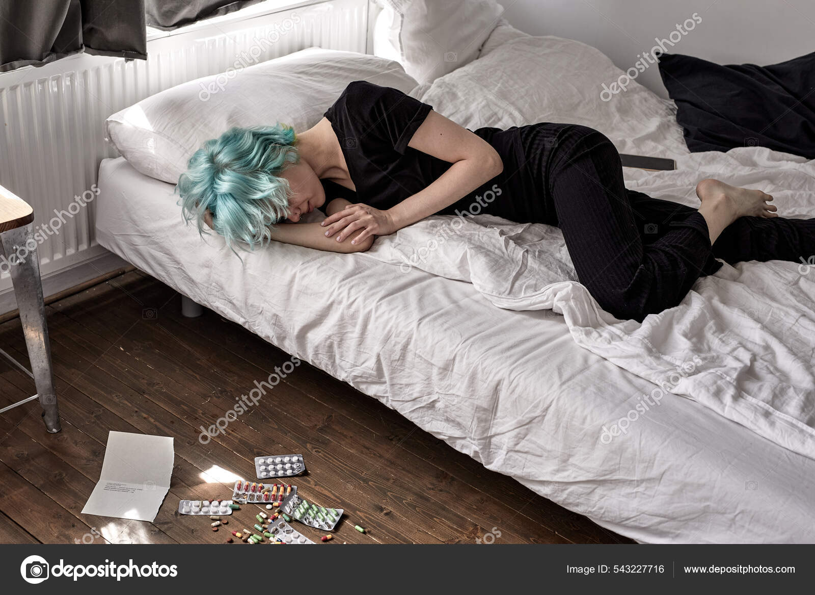 Pills spread on floor, crying woman lying on bed after taking pills ...