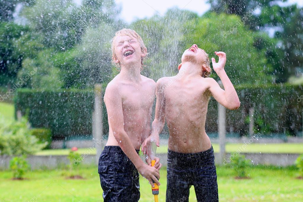 Two happy boys playing in the garden with watering hose — Stock Photo ...