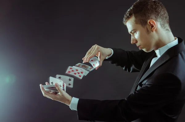 Magician holding cards. Wearing black suit. Studio shot against Stock ...