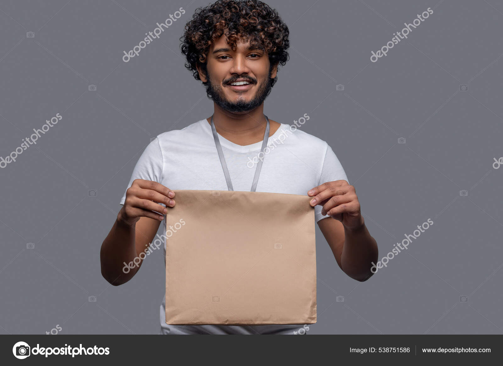 Joyous man with a package posing against the gray background Stock ...