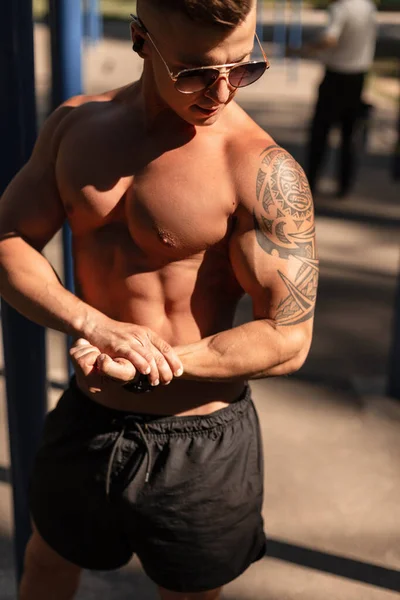 Handsome bodybuilder guy with sunglasses and wireless headphones with ...