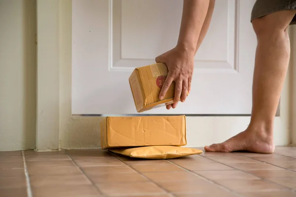 Woman collects parcel at door. box near door on floor. Online shopping ...