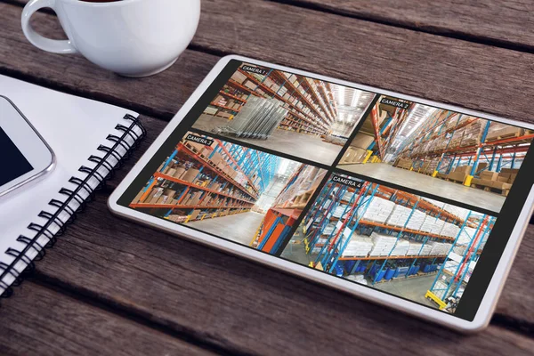 Tablet with views of warehouse from security cameras on screen lying on ...