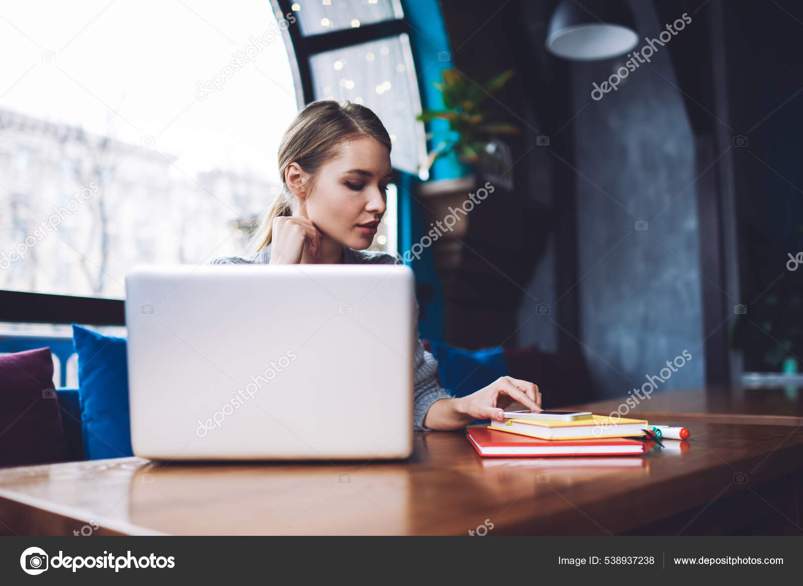 Young Concentrated Female Remote Worker Opened Laptop Using Mobile ...