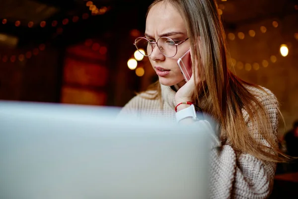Crop female remote worker in casual outfit with eyewear looking down ...