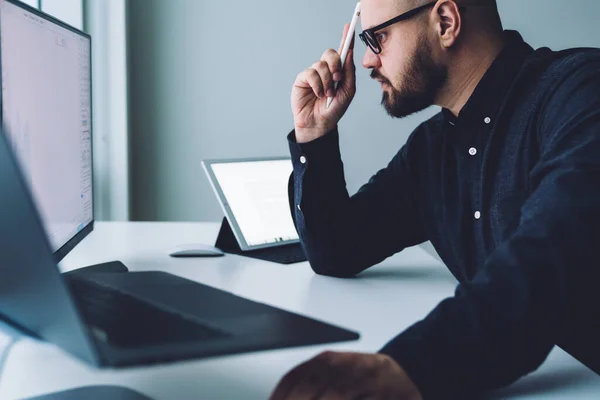 Side view of crop young focused male analyst touching forehead with ...