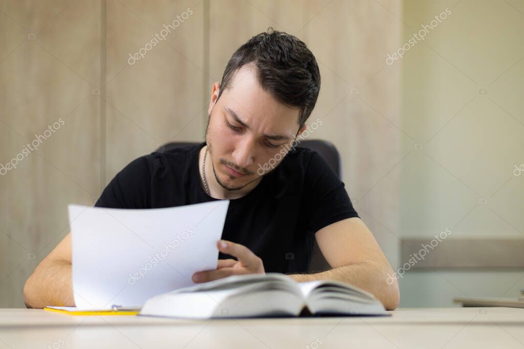 Joven estudiante masculino en el proceso de aprendizaje con una pluma y ...