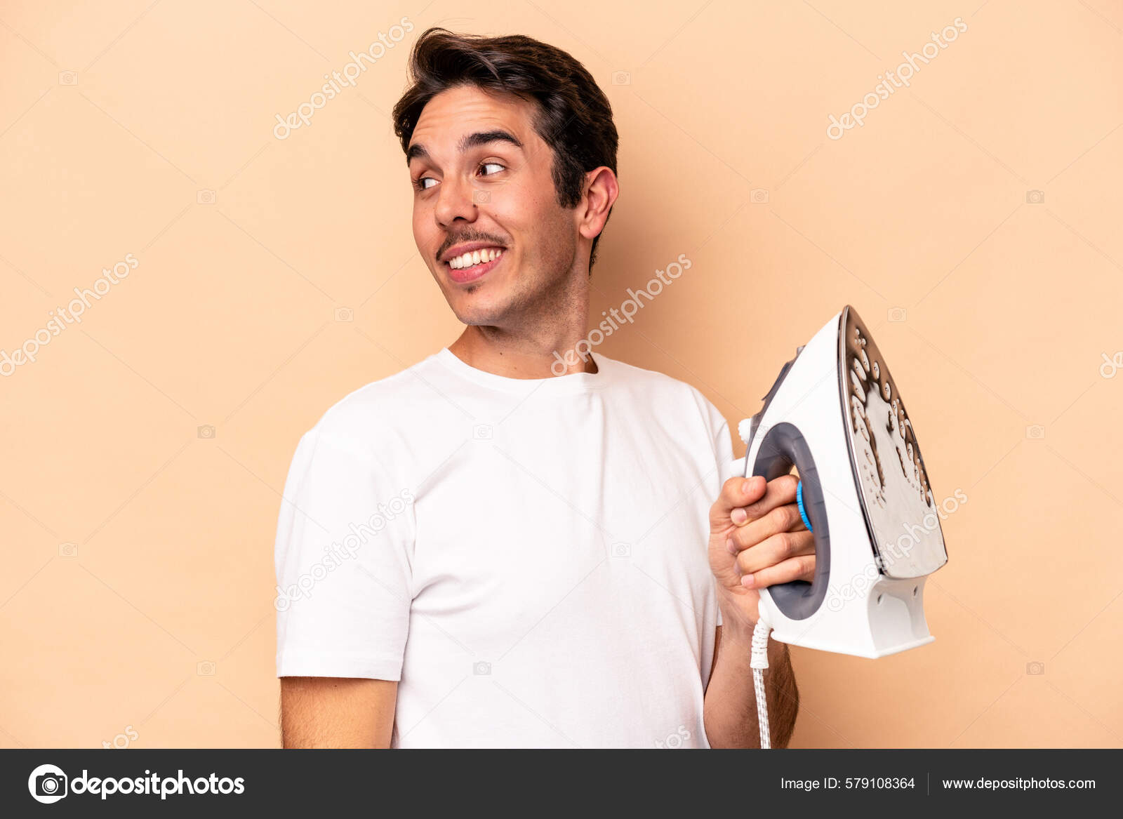 Young Caucasian Man Holding Iron Isolated Beige Background Looks Aside ...