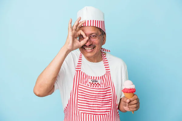 Senior american ice cream man holding an ice cream isolated on blue ...