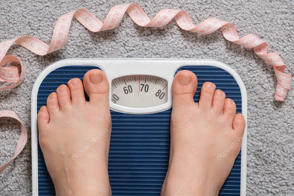 Mujeres pies desnudos en balanzas de piso y cinta métrica, peso 60-70 ...