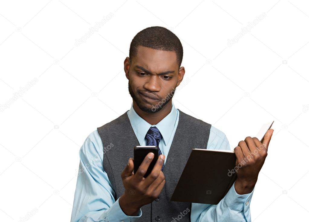Skeptical man looking at phone holding book Stock Photo by ...