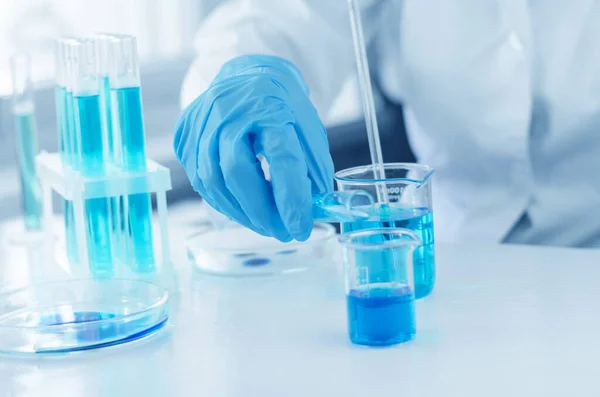 Las manos del científico sostienen un frasco y una pipeta de ...