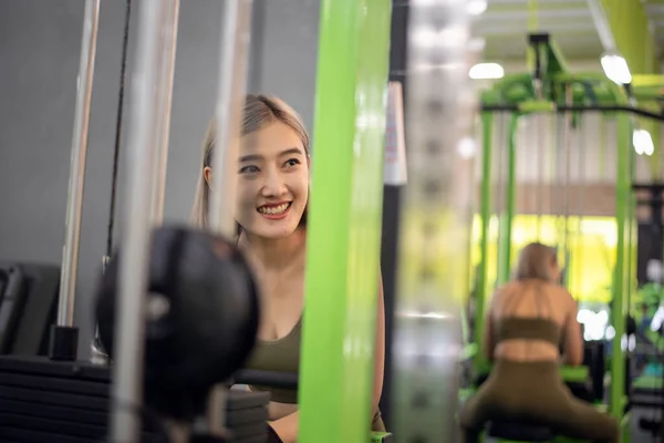Strong young Asian woman exercising with pulldown machine during a ...