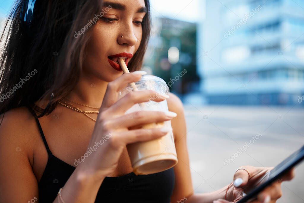 Chica atractiva bebiendo caf fr o y mirando en el tel fono inteligente. Adolescente con estilo ...