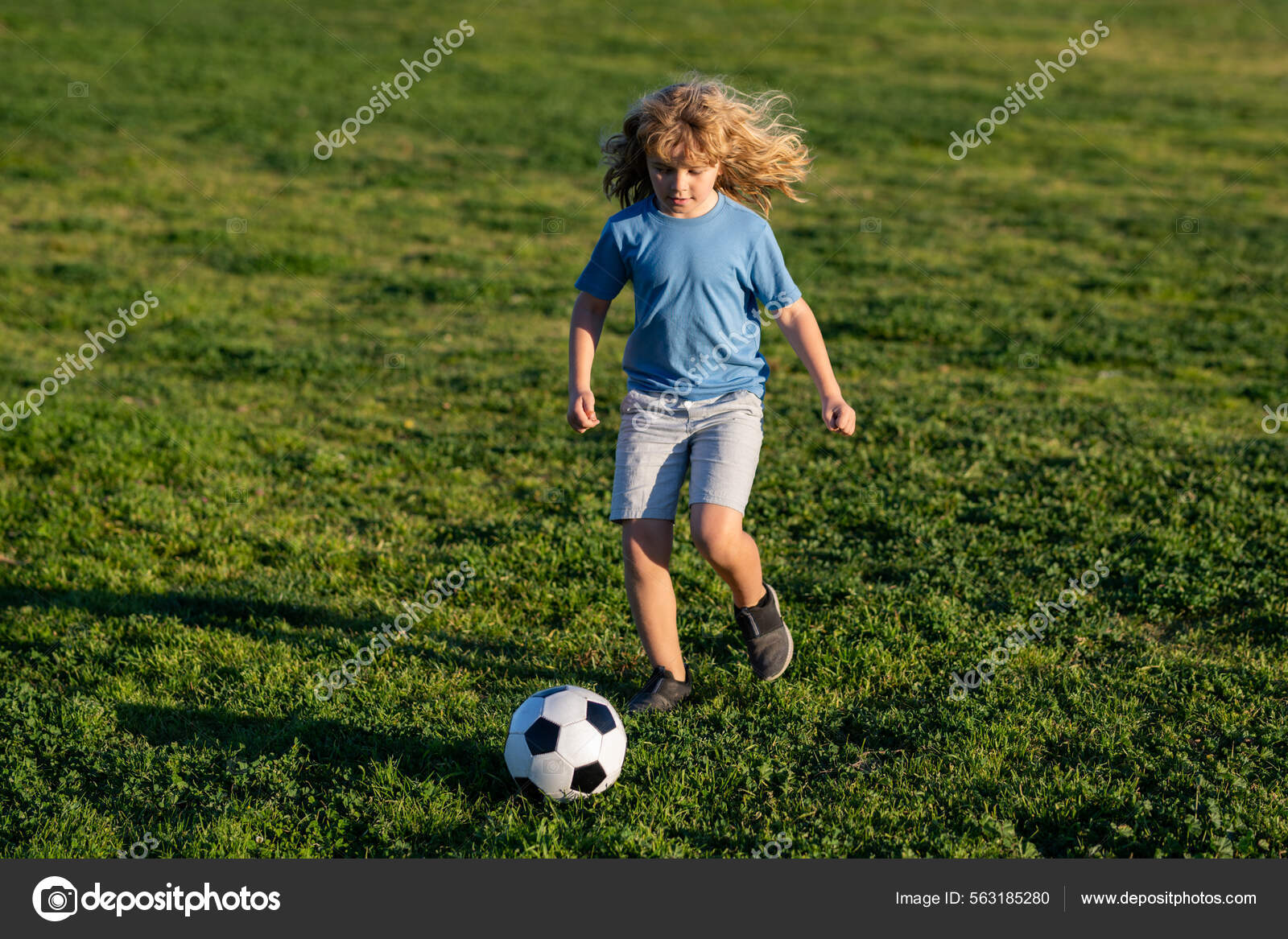 Soccer kid. Kids play football on summer stadium field. Little child boy kicking ball. Little ...