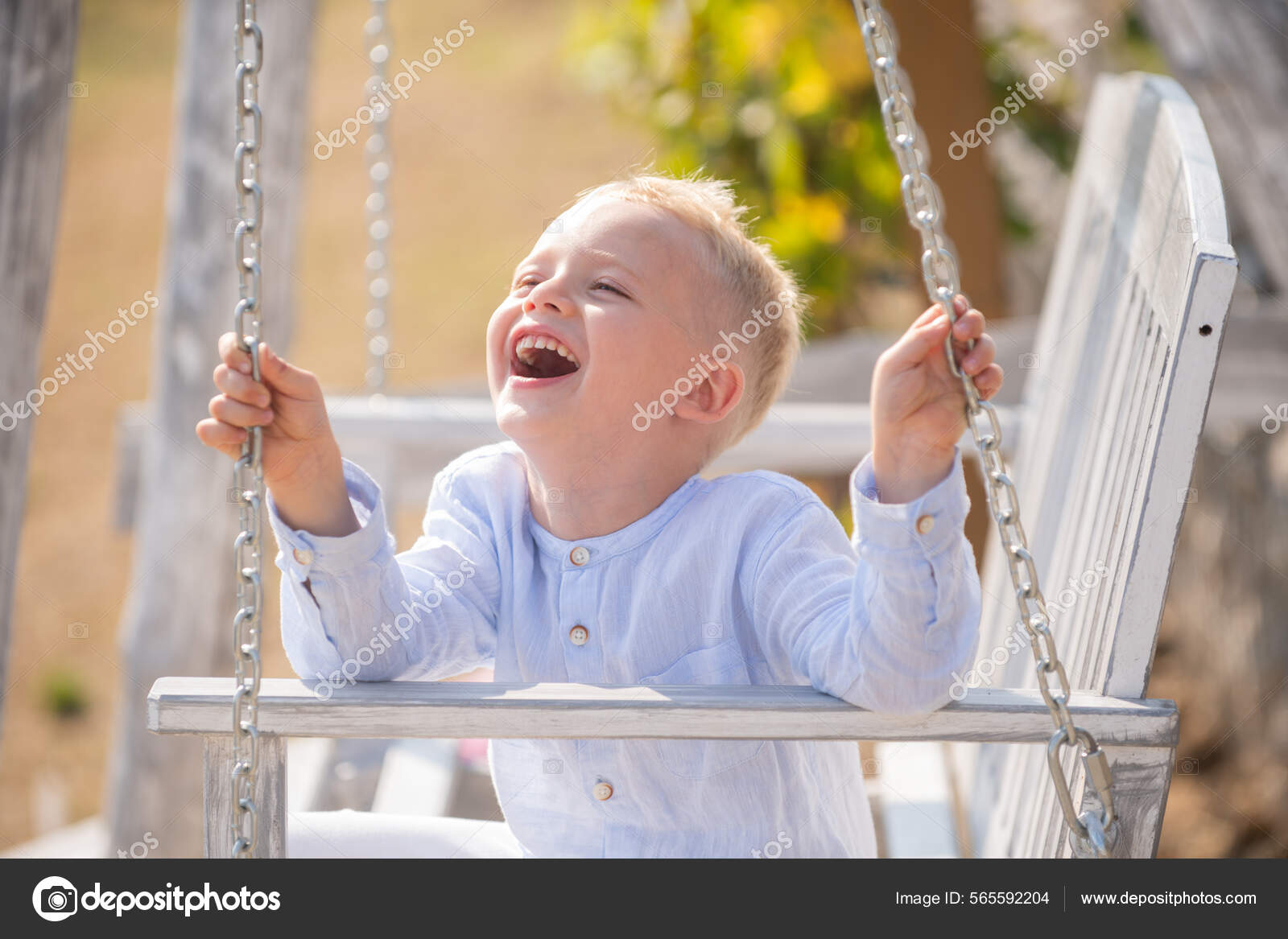 Happy child boy laughing and swinging on a swing at the park in summer. Kids happiness and smile ...