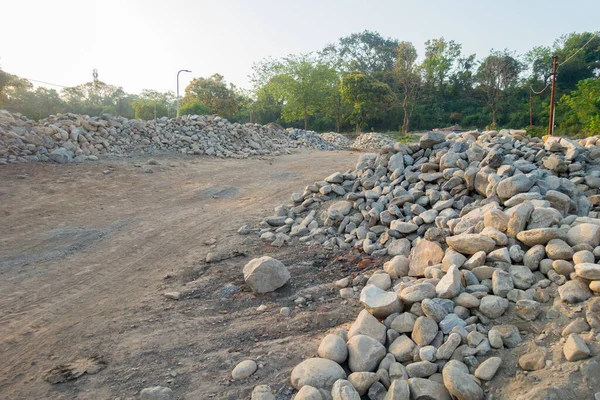 A pile of stone alongside road for constructing a stone retaining wall ...