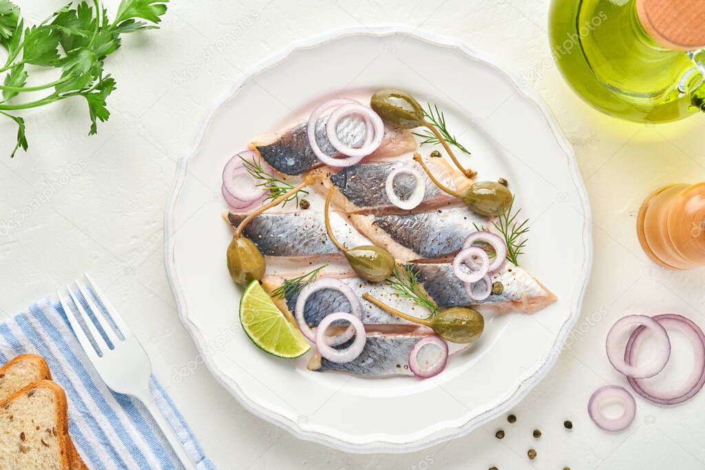 Arenque salado con especias, hierbas y cebolla en plato blanco sobre ...
