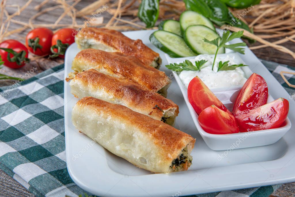 Rollos de borek turcos con espinacas en el plato blanco. Un pastel turco tradicional, rulo borek ...