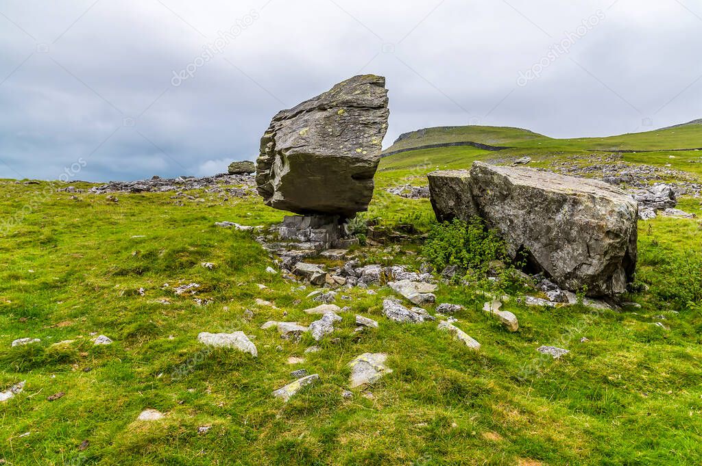 Una vista de un glaciar errático descansando en el pavimento de piedra caliza en las laderas del ...
