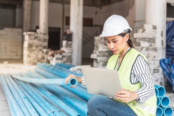 Asian woman construction engineer using notebook computer for checking the PVC pipe, to meet the ...