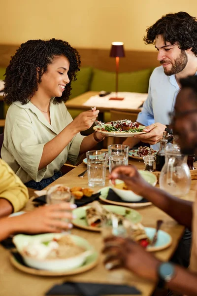 Friends Are Sharing Food In A Restaurant At The Dinner Table Stock