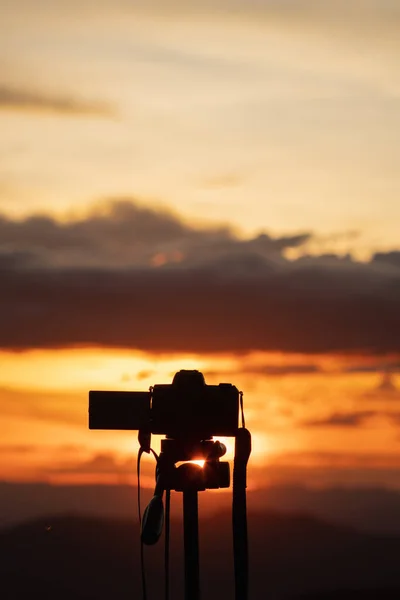 Silhouette of camera mounted on tripod to capture time lapse video of ...