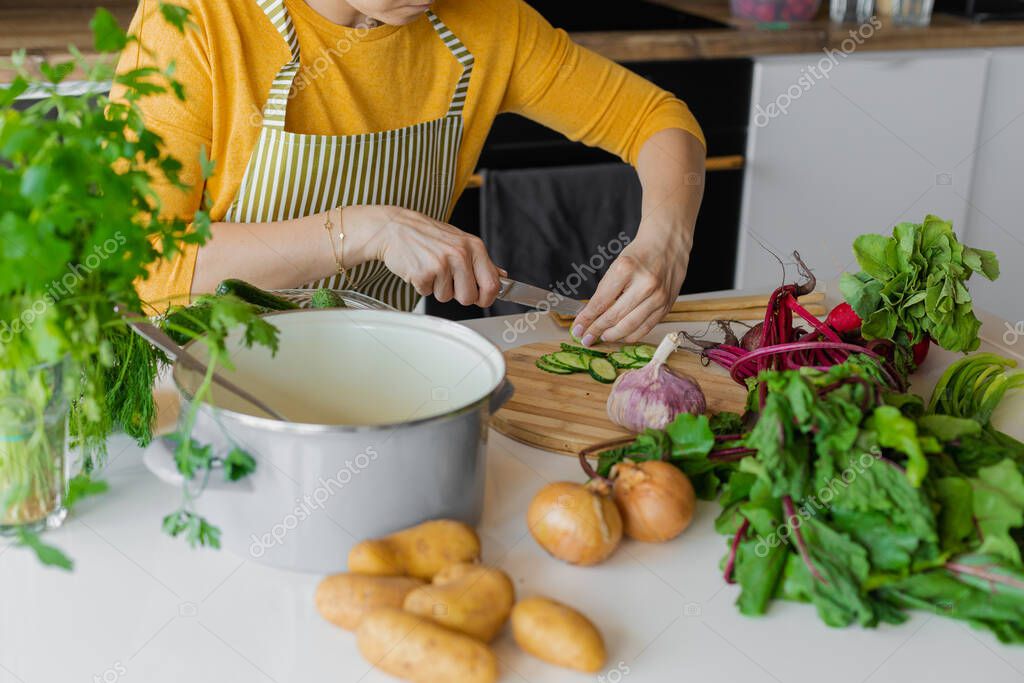 Mujer irreconocible en delantal picando verduras frescas para sopa y ...
