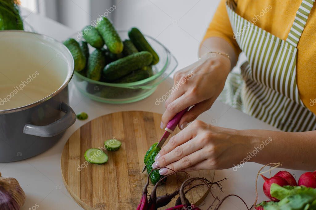 Manos femeninas irreconocibles picando pepinos aromáticos sobre tabla ...