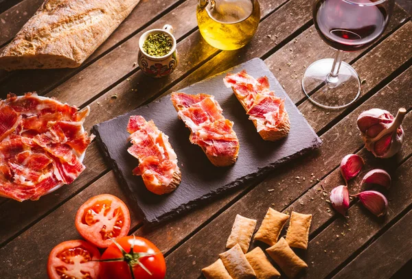 Tostadas de jamón ibérico en un plato de pizarra sobre una mesa de ...