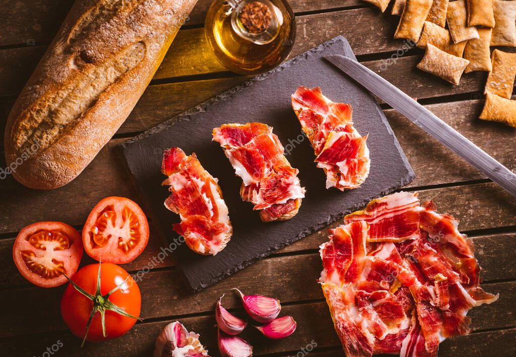 Tostadas de jamón ibérico en un plato de pizarra sobre una mesa de ...