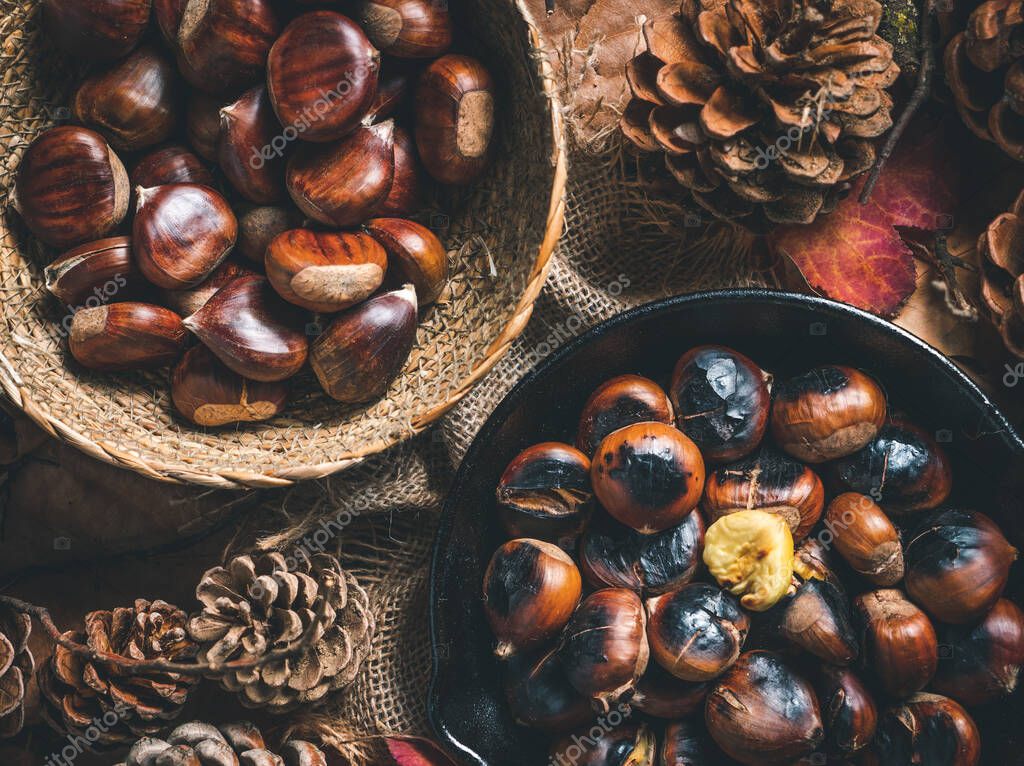 Castañas crudas y tostadas en una pequeña sartén de hierro y un tazón ...