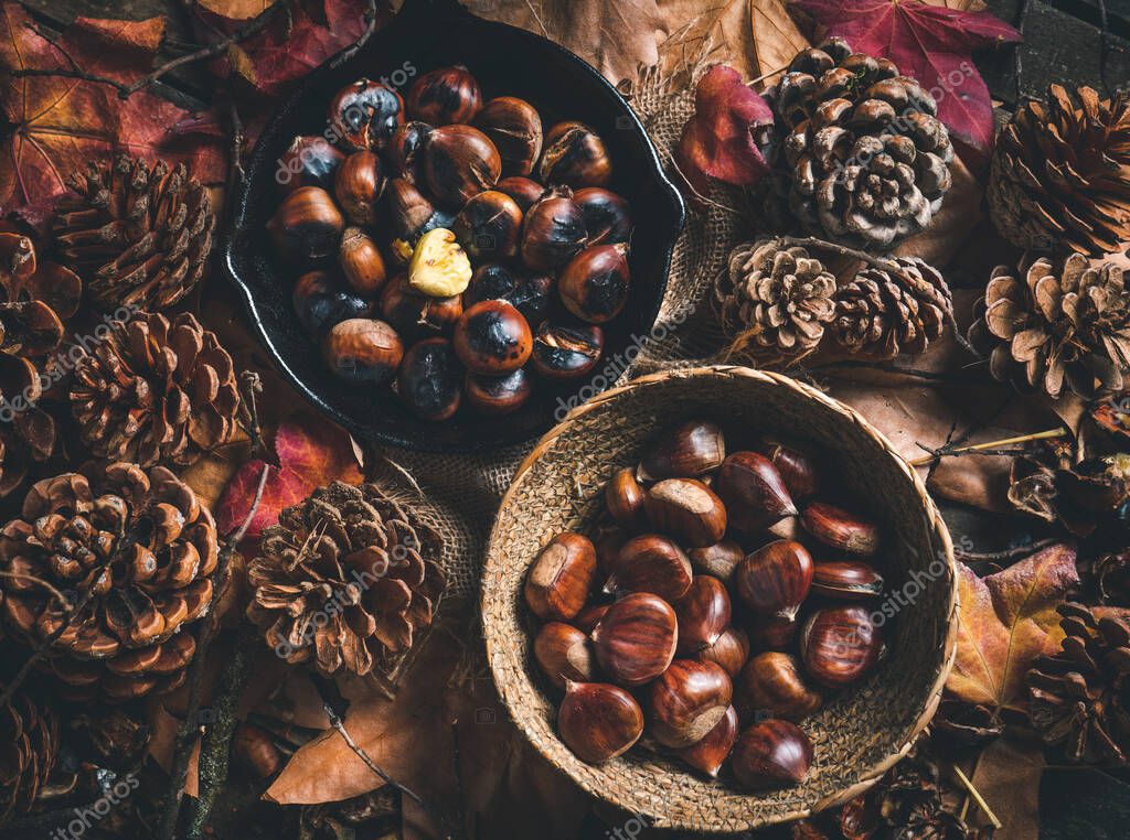 Castañas crudas y tostadas en una pequeña sartén de hierro y un tazón ...