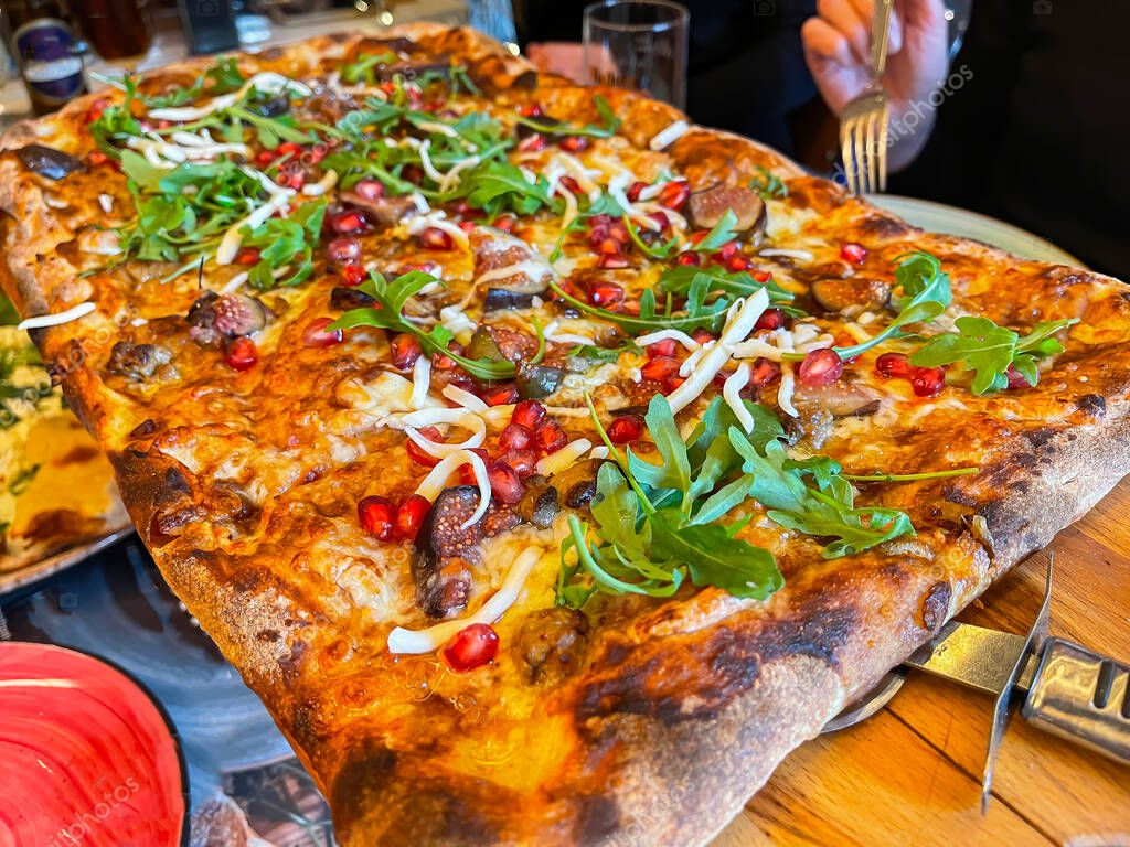 primer plano de una pizza cuadrada gigante en el centro de una mesa ...