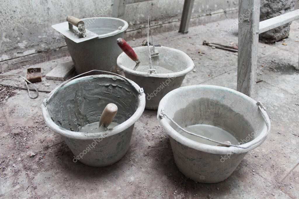 Cubo de construcción, paleta y mezcla de hormigón. En un sitio de ...