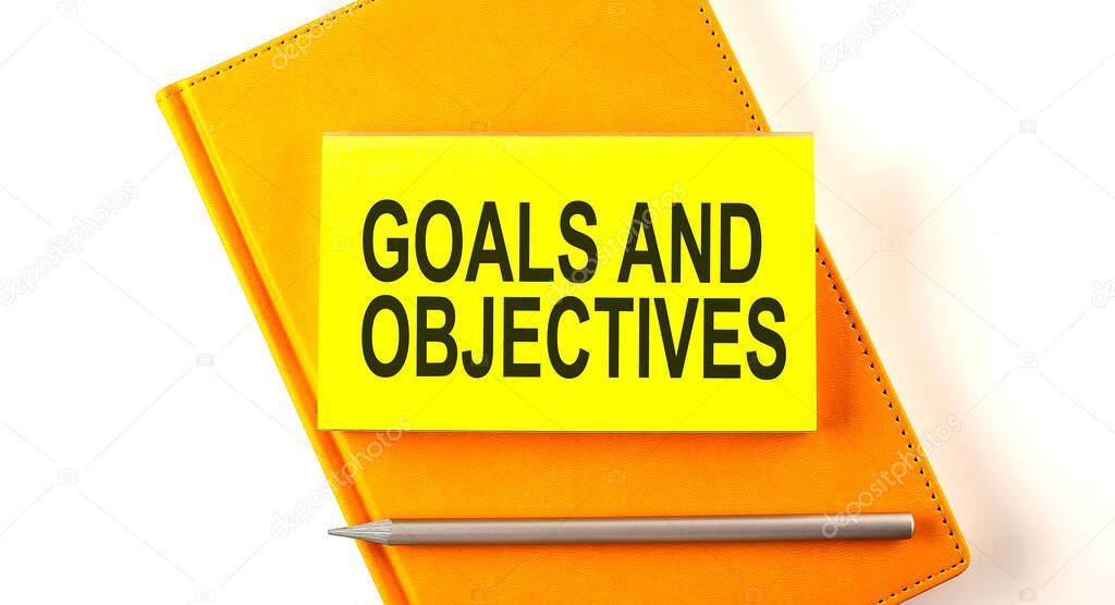 Texto OBJETIVOS Y OBJETIVOS en la etiqueta engomada en el cuaderno ...