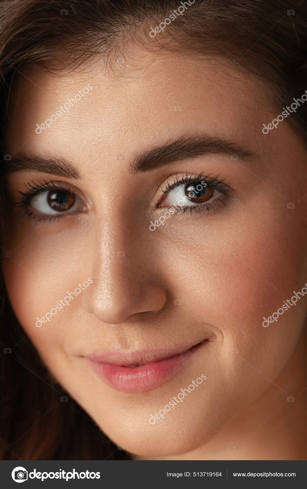 Close-up portrait of young beautiful girl without makeup isolated over dark studio background ...