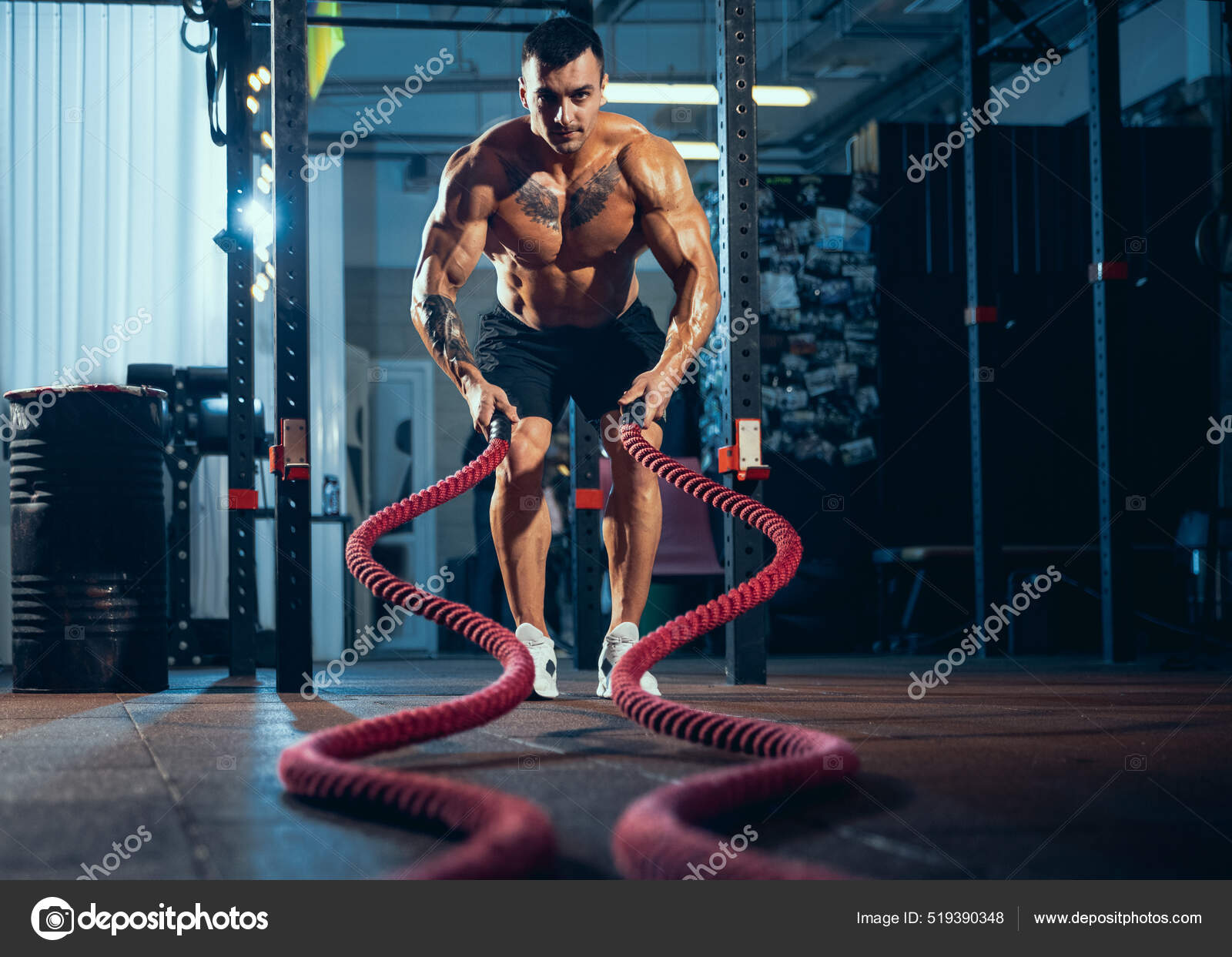 Young man, muscled athlete, bodybuilder training alone at sport gym ...