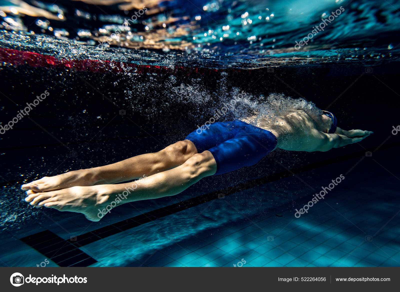 Underwater shooting. One male swimmer training at pool, indoors ...