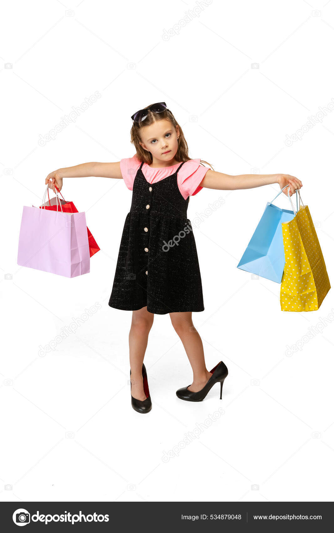 Studio shot of pretty little cute kid standing with multi colored ...