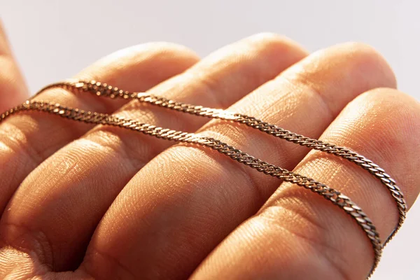 Gold chain on human hand. Closeup hands of jeweler at work in jewelry ...