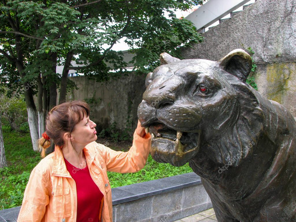 Mujer mira admirablemente tigre de bronce y tomó su colmillo con los ...