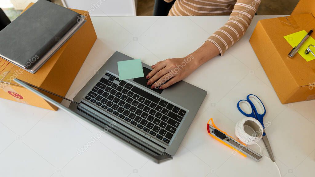 Una mujer que trabaja en casa con cajas de cart n y una computadora port til para recibir ...